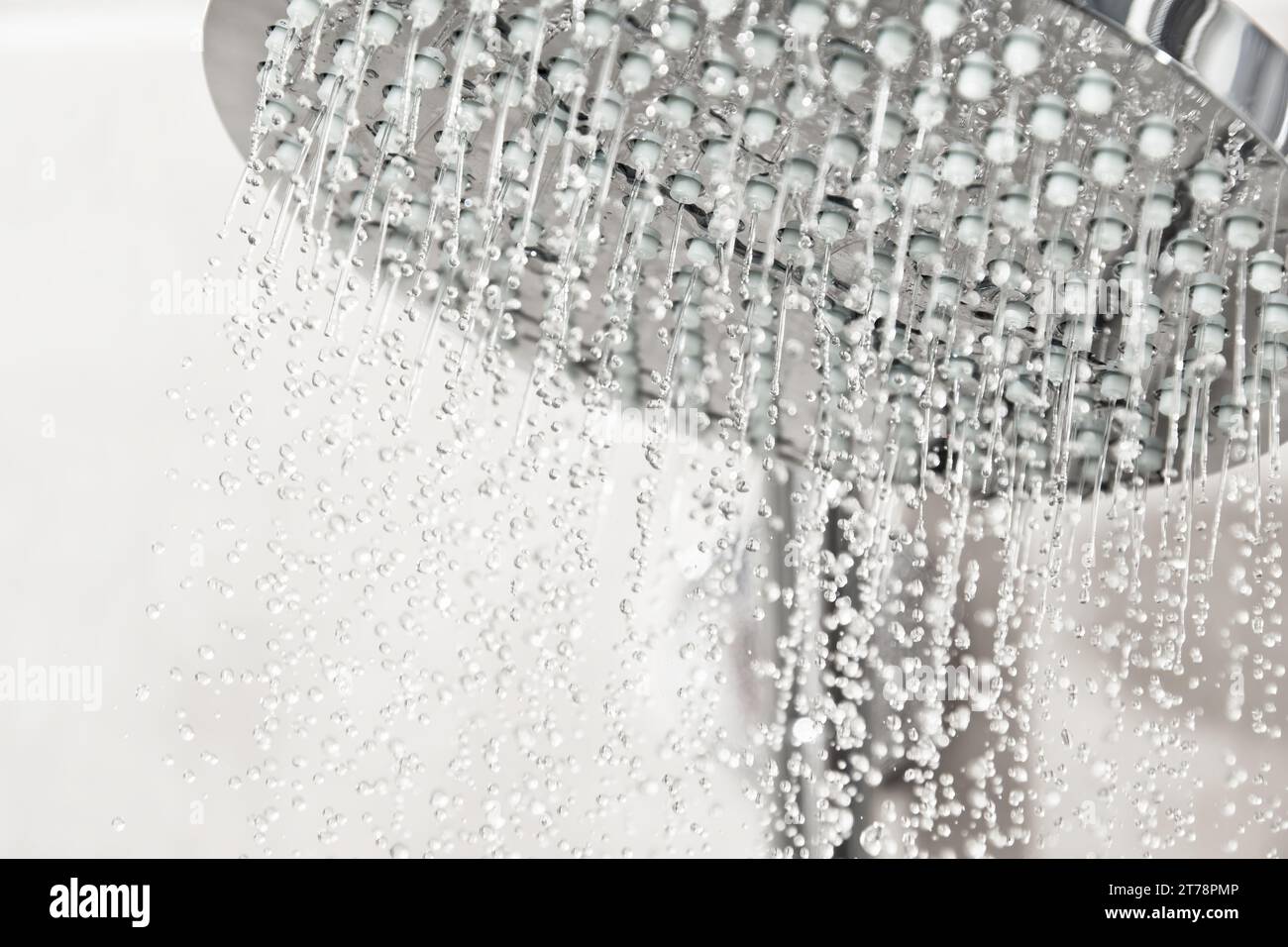 Clean water drops pours from the shower head in the light bathroom ...