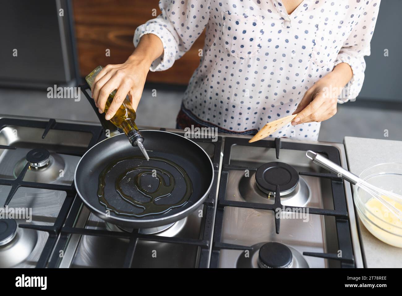 Midsection of mature caucasian woman pouring oil in pan making ...