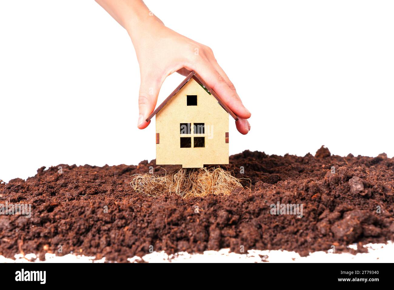 Small wooden house with roots from a plant is being carefully planted ...