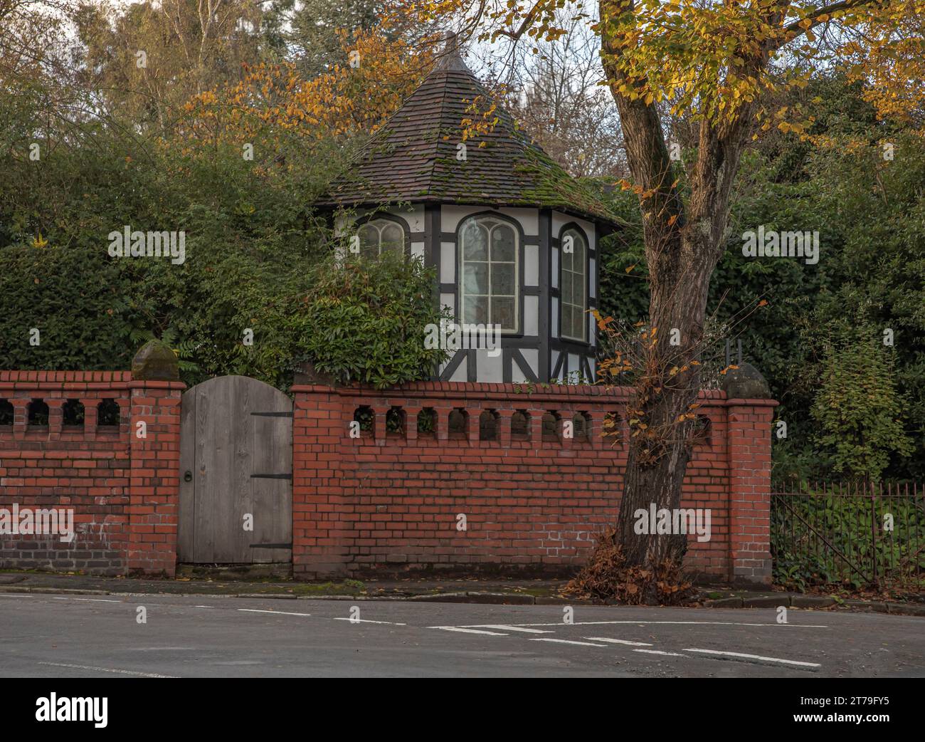 Hexygon shapped black and white building behind a red brick wall with ...