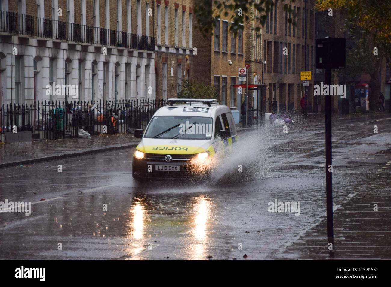 London, UK. 14th November 2023. A police car splashes through a large ...