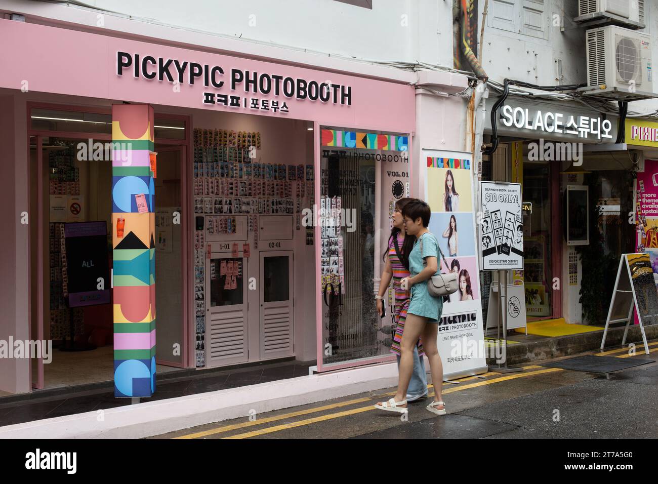 Two chinese women are walking to the shop frontage to check out the ...