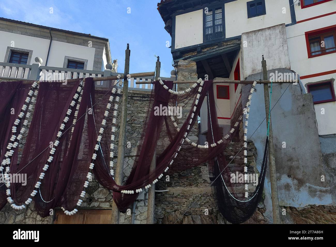 traditional Basque house with a large, dark red fishing net hanging in ...