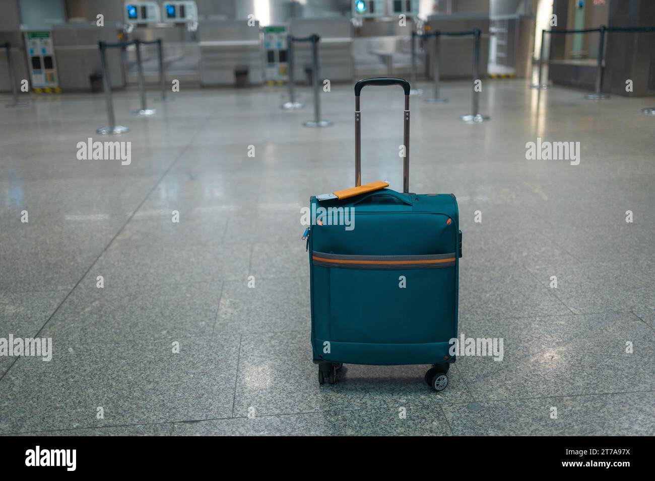 Blue suitcase in an empty airport hall, traveler cases in the departure ...