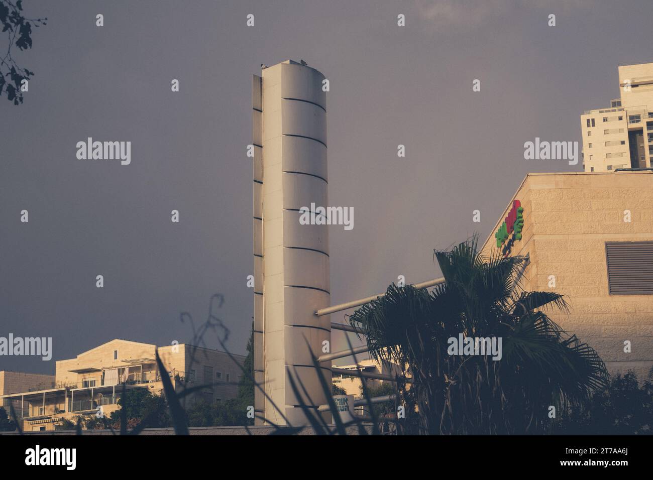 white cylindrical building with a rainbow in the sky, taken in a city ...