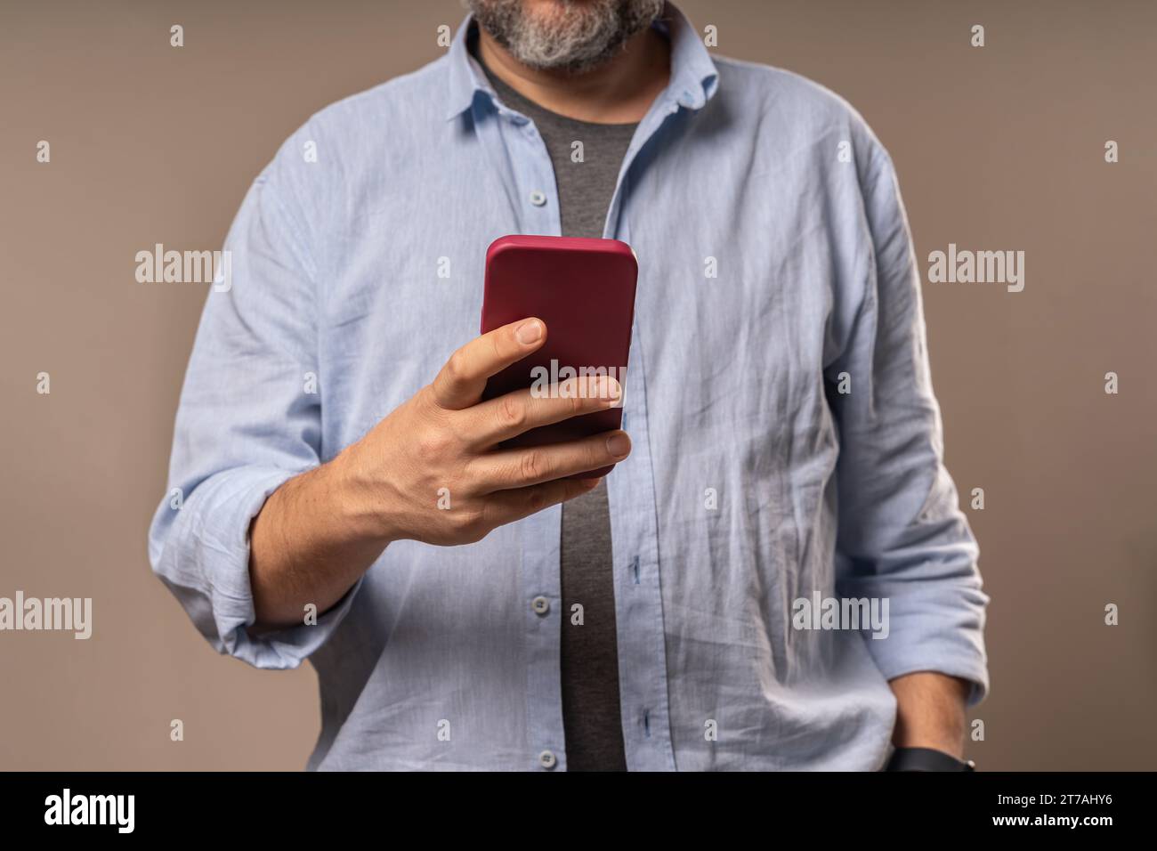 A middle-aged man is engaged with a smartphone, capturing the essence ...