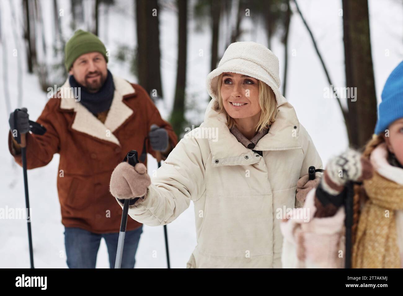 Happy young blond woman in warm winter hat and coat practicing ...