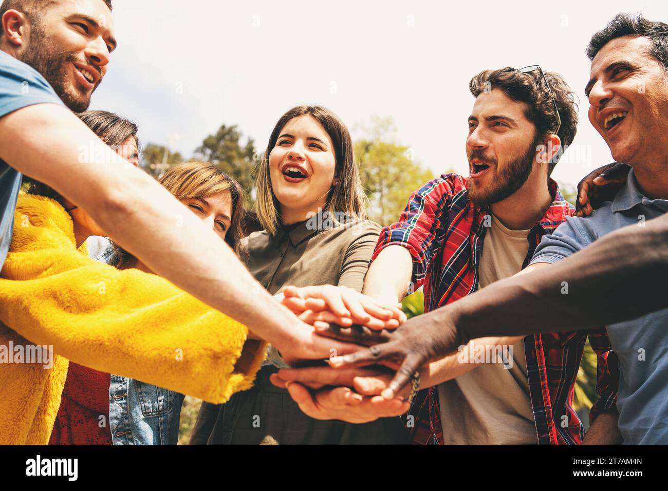 Group of friends with hands together in a show of unity and teamwork, celebrating community and ...
