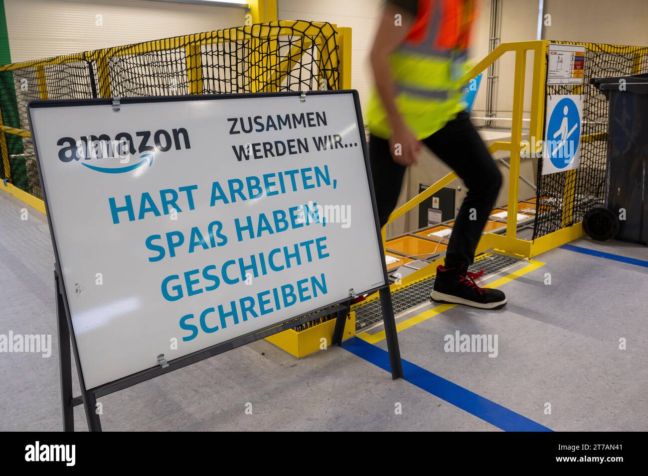 Erding, Germany. 14th Nov, 2023. An Amazon employee walks past a sign ...
