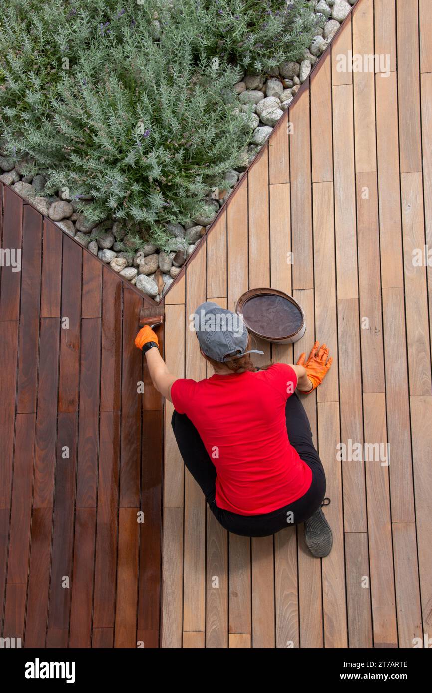 A worker painting wooden deck with protective decking oil bucket top ...