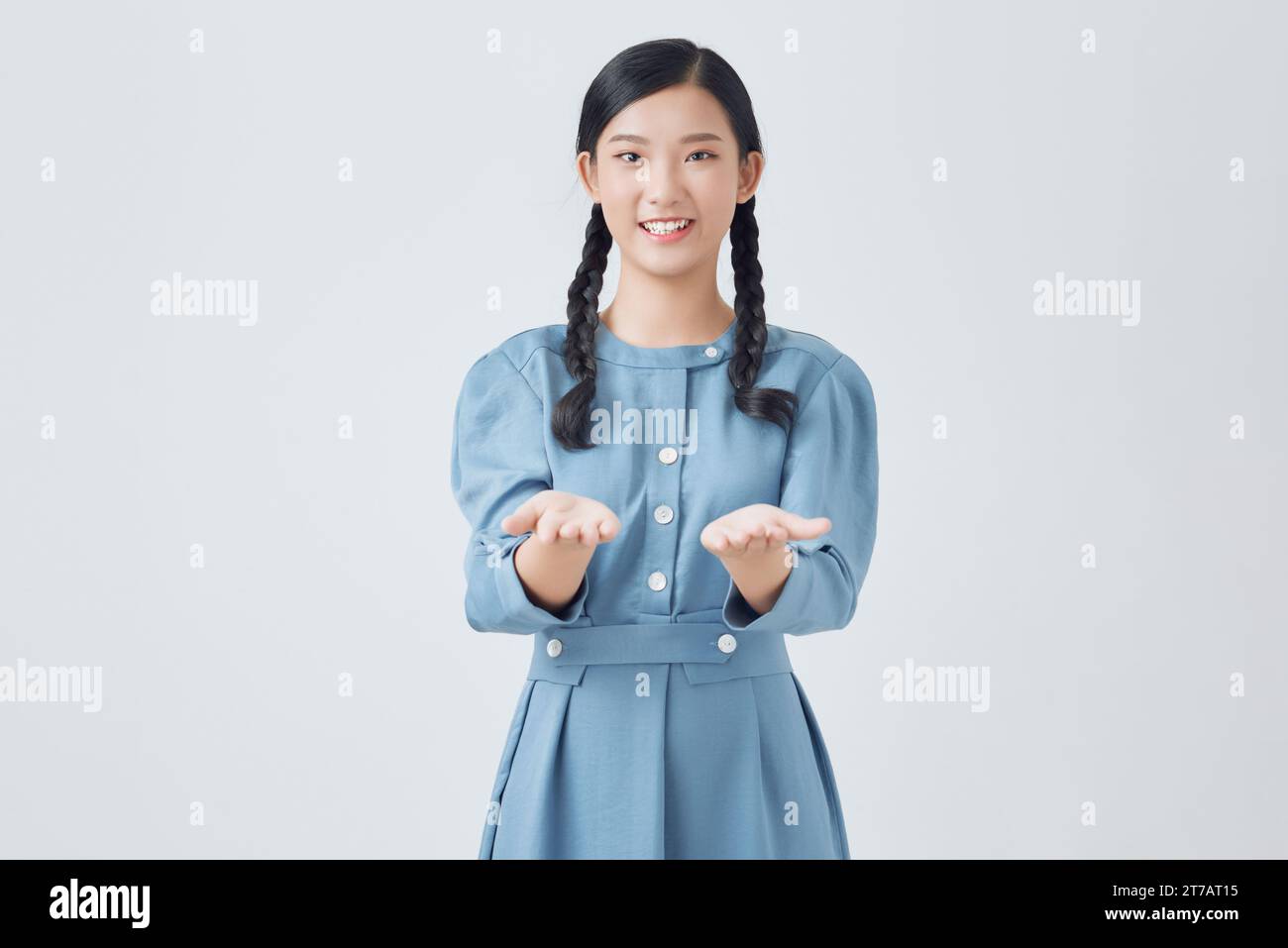 Asian cute girl smiling and showing hand to present something isolated ...
