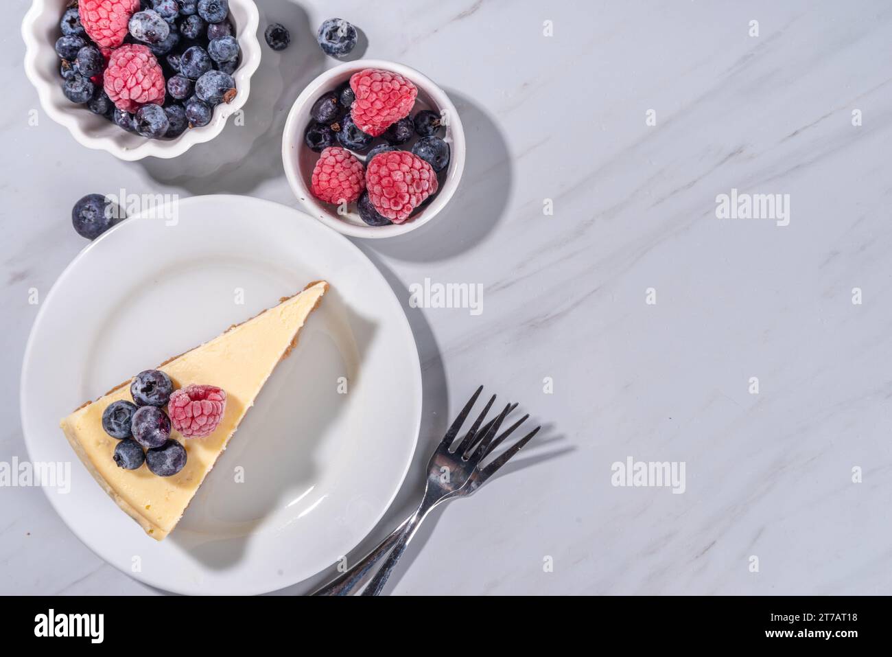 Cheesecake portion slice on plate, with raspberry on blueberry on white ...