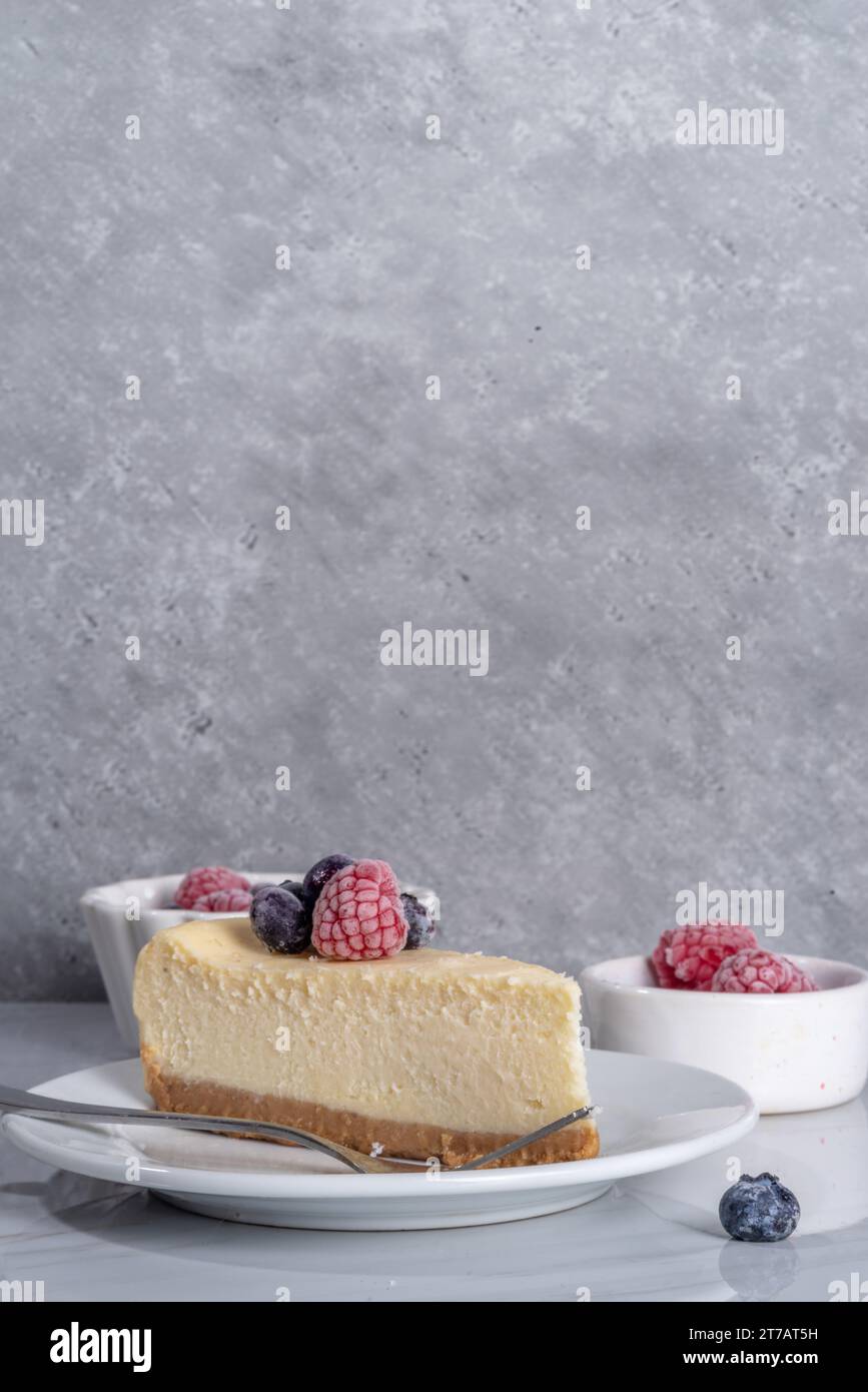 Cheesecake portion slice on plate, with raspberry on blueberry on white ...