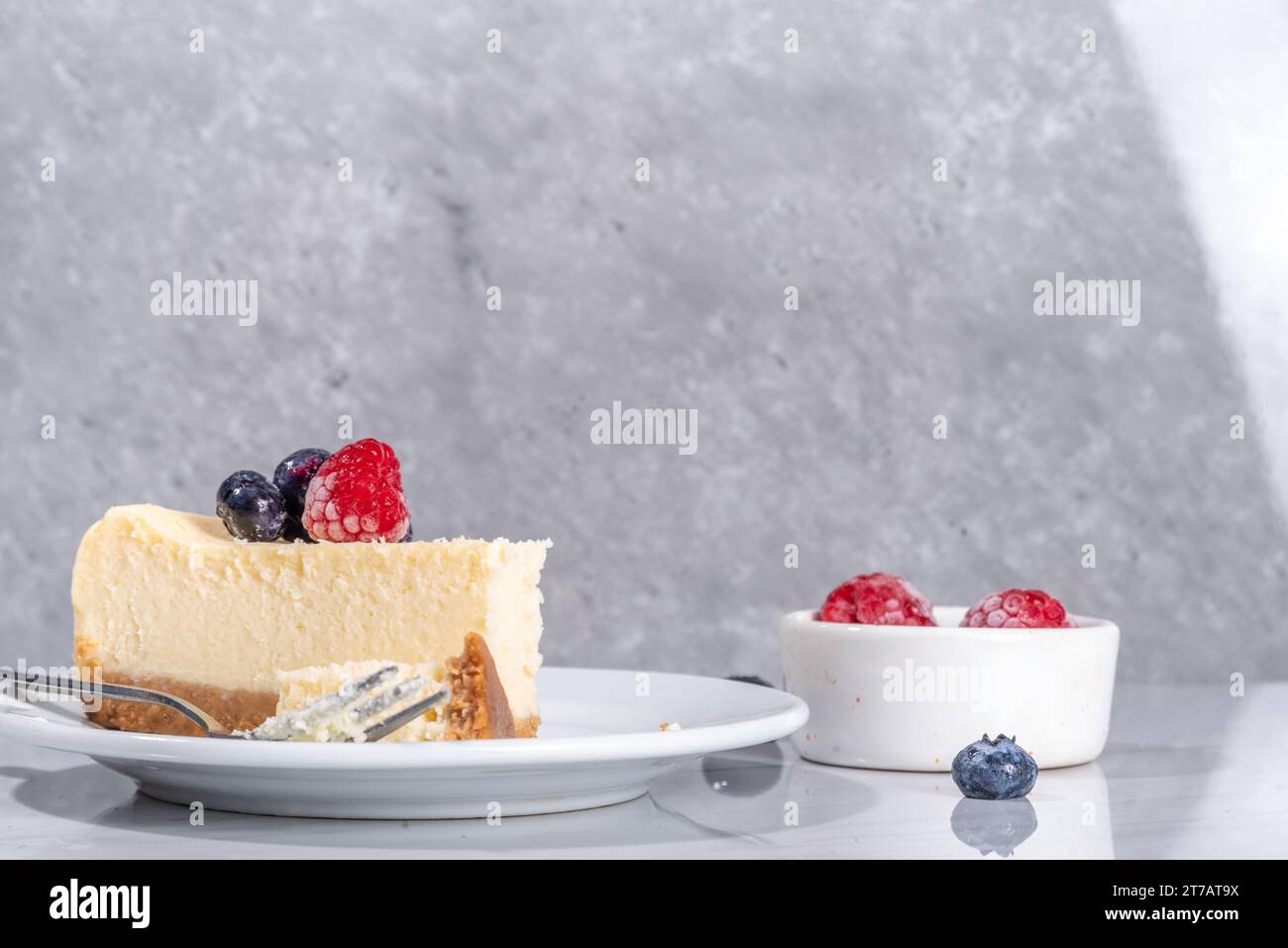 Cheesecake portion slice on plate, with raspberry on blueberry on white ...
