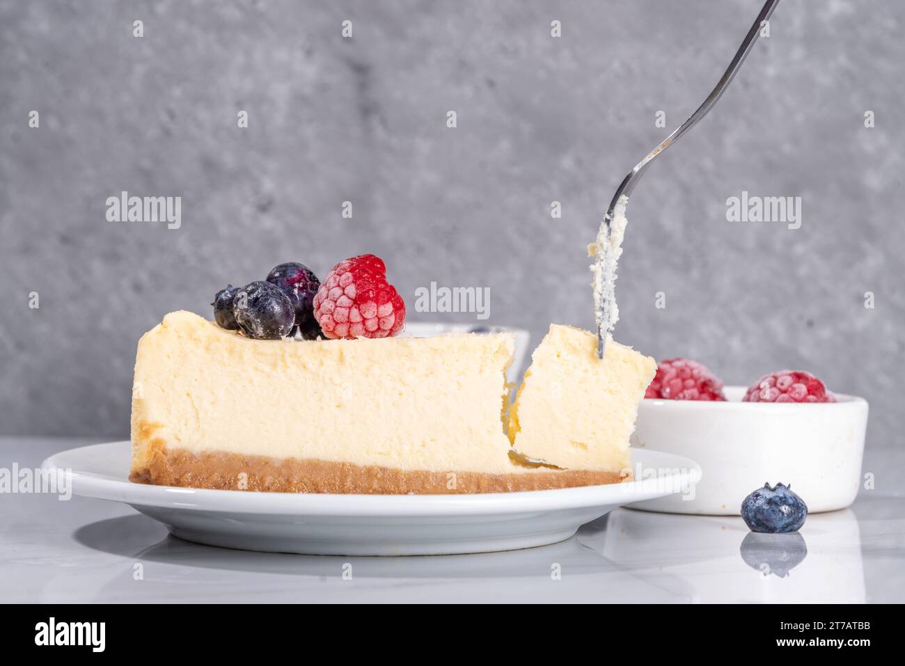 Cheesecake portion slice on plate, with raspberry on blueberry on white ...
