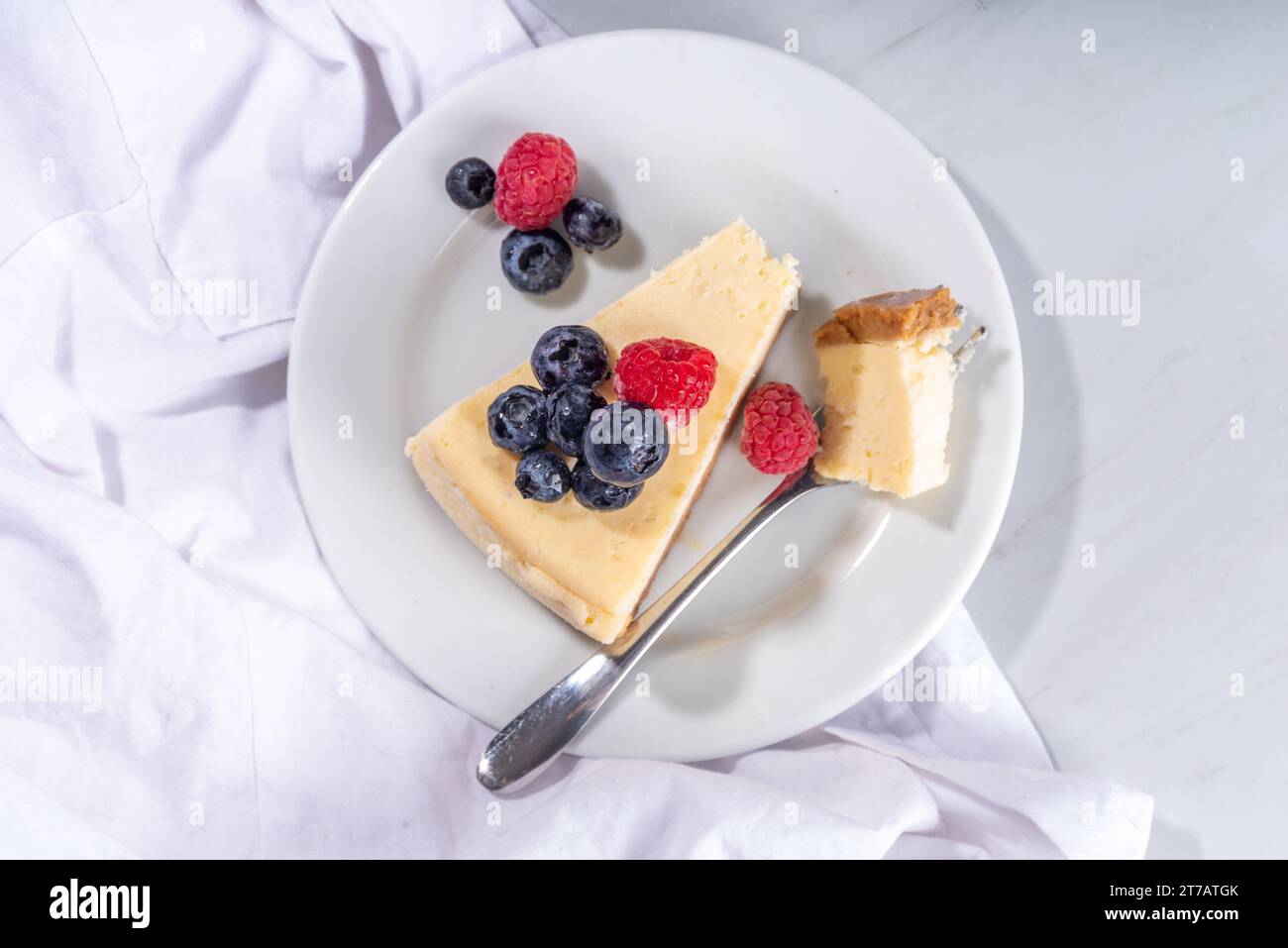 Cheesecake portion slice on plate, with raspberry on blueberry on white ...