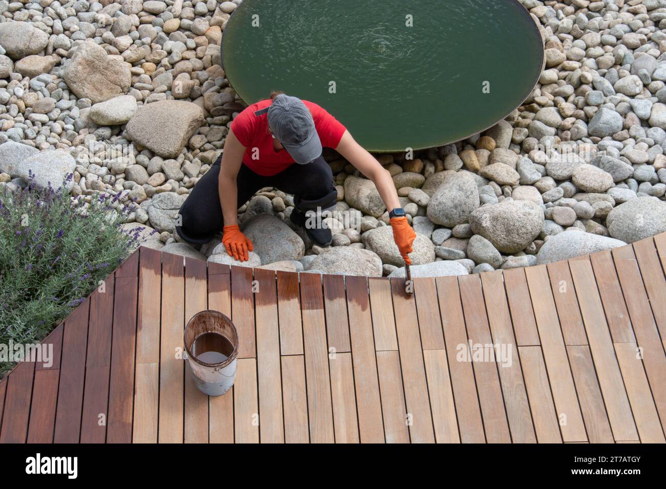 Wood oil application, workwoman maintaining exterior house garden ...
