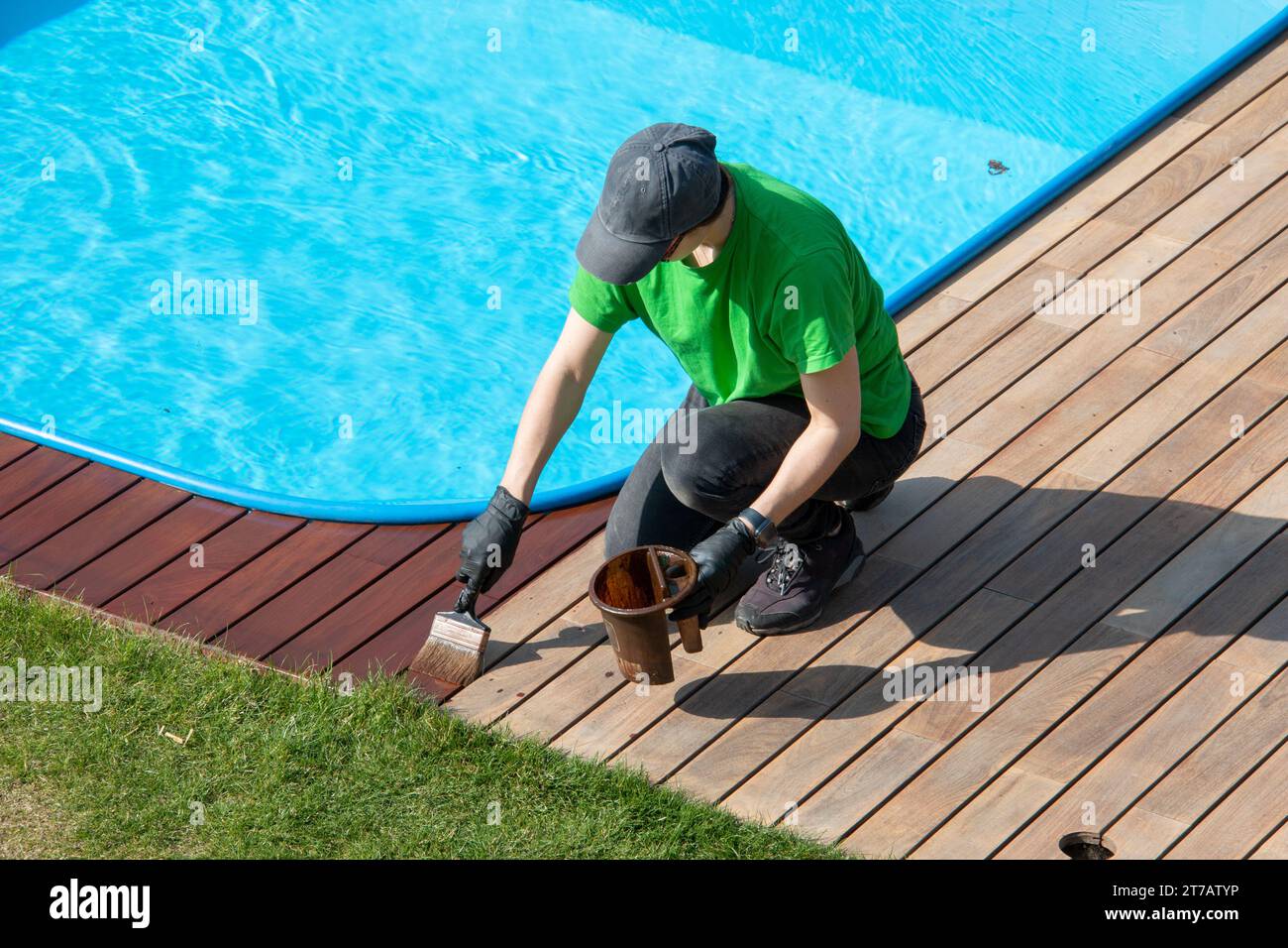 Female worker painting exterior wooden pool deck with decking oil Stock ...