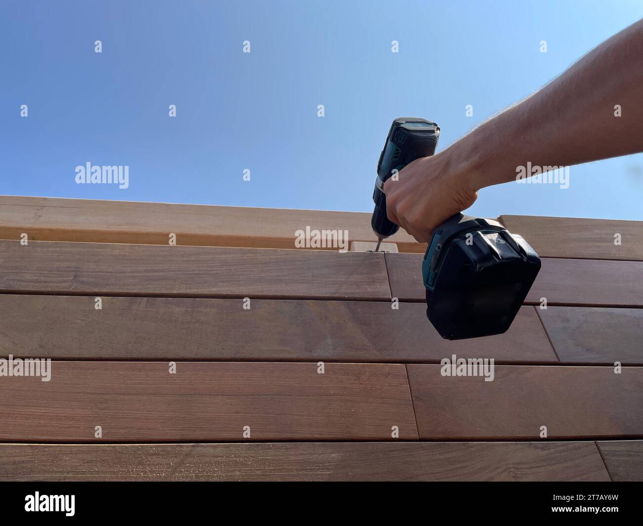 Carpentry worker hand with electric screwdriver building wooden deck ...