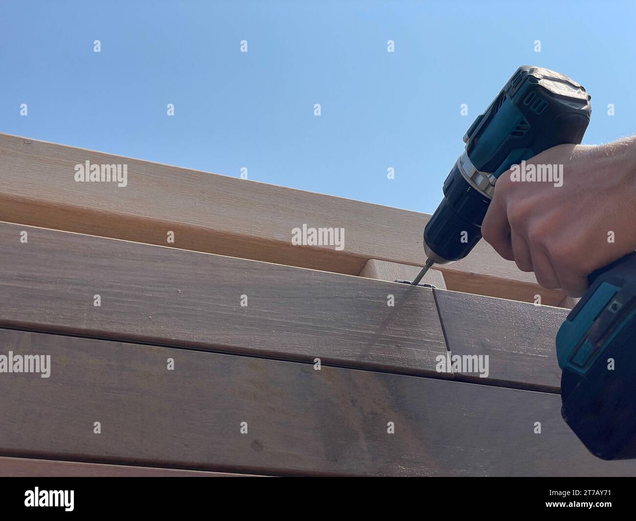 Carpentry worker building wooden deck siding boards with electric ...