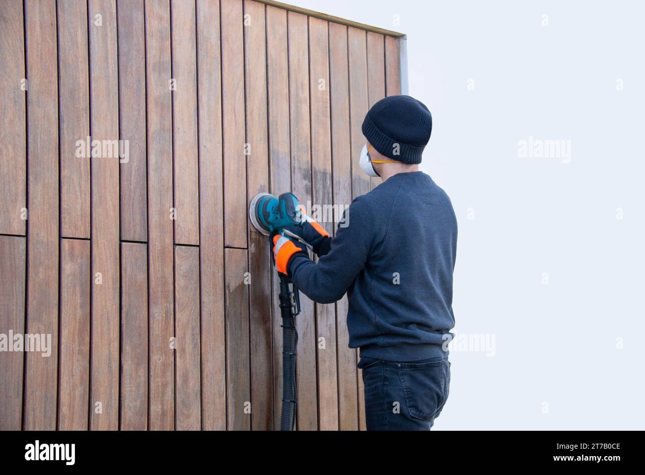 Professional renovation of hardwood cladding, man sanding, removing ...