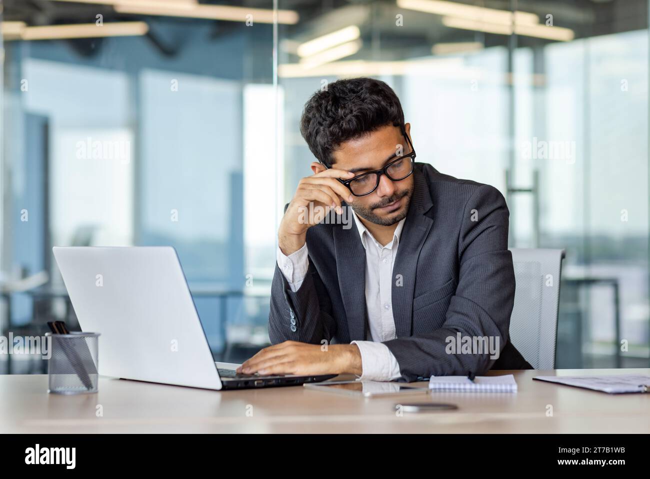 Tired male office worker sitting at desk in front of laptop at desk ...