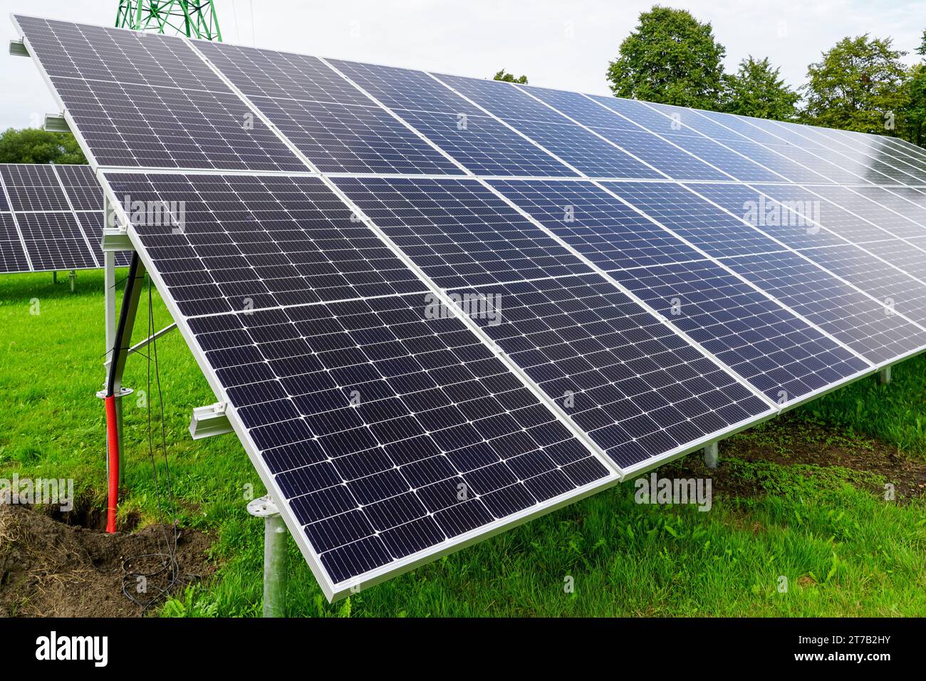 Installation of solar panels on metal frames in a green meadow ...