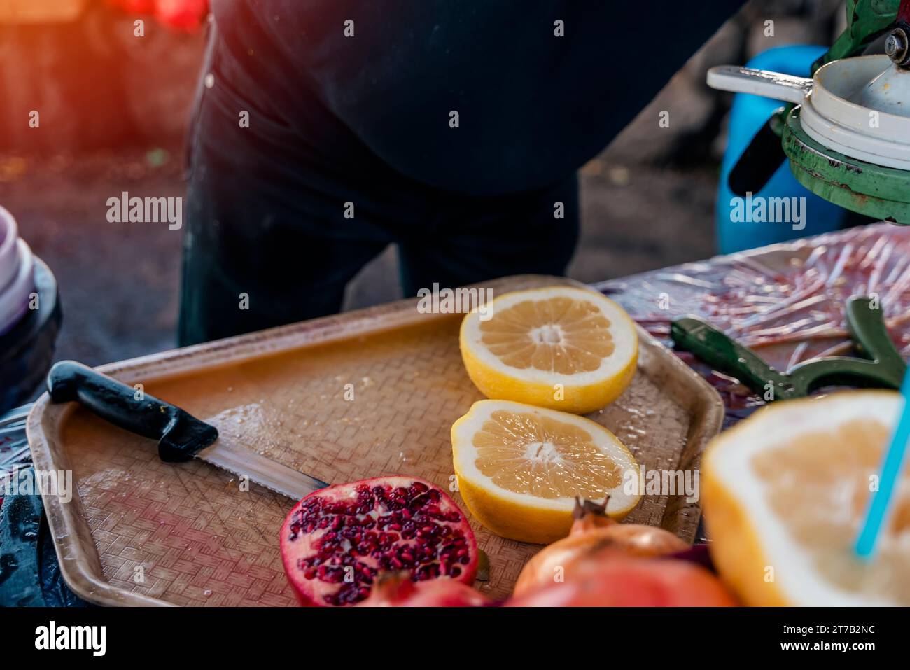 a man cutting a pomelo fruit on a board and making juice at the market ...
