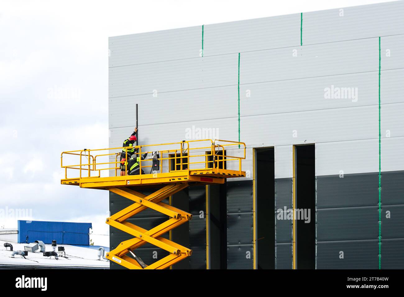 A large yellow self propelled scissor lift platform with workers ...