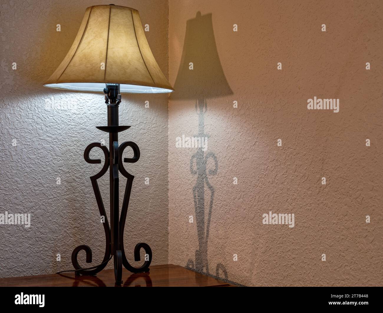 Illuminated table lamp in the corner of a bedroom with a shadow on the ...