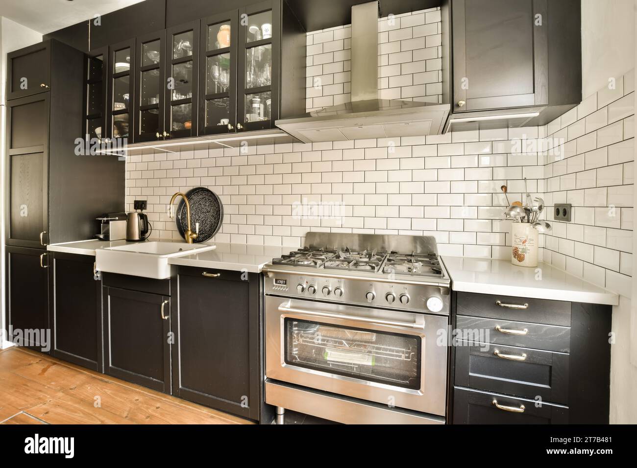 a kitchen with black cabinets and white subway tiles on the wall behind ...