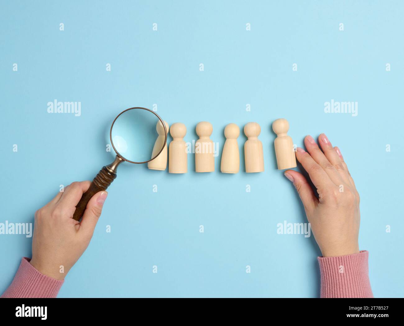 Wooden men and a magnifying glass on a blue background. Recruitment ...