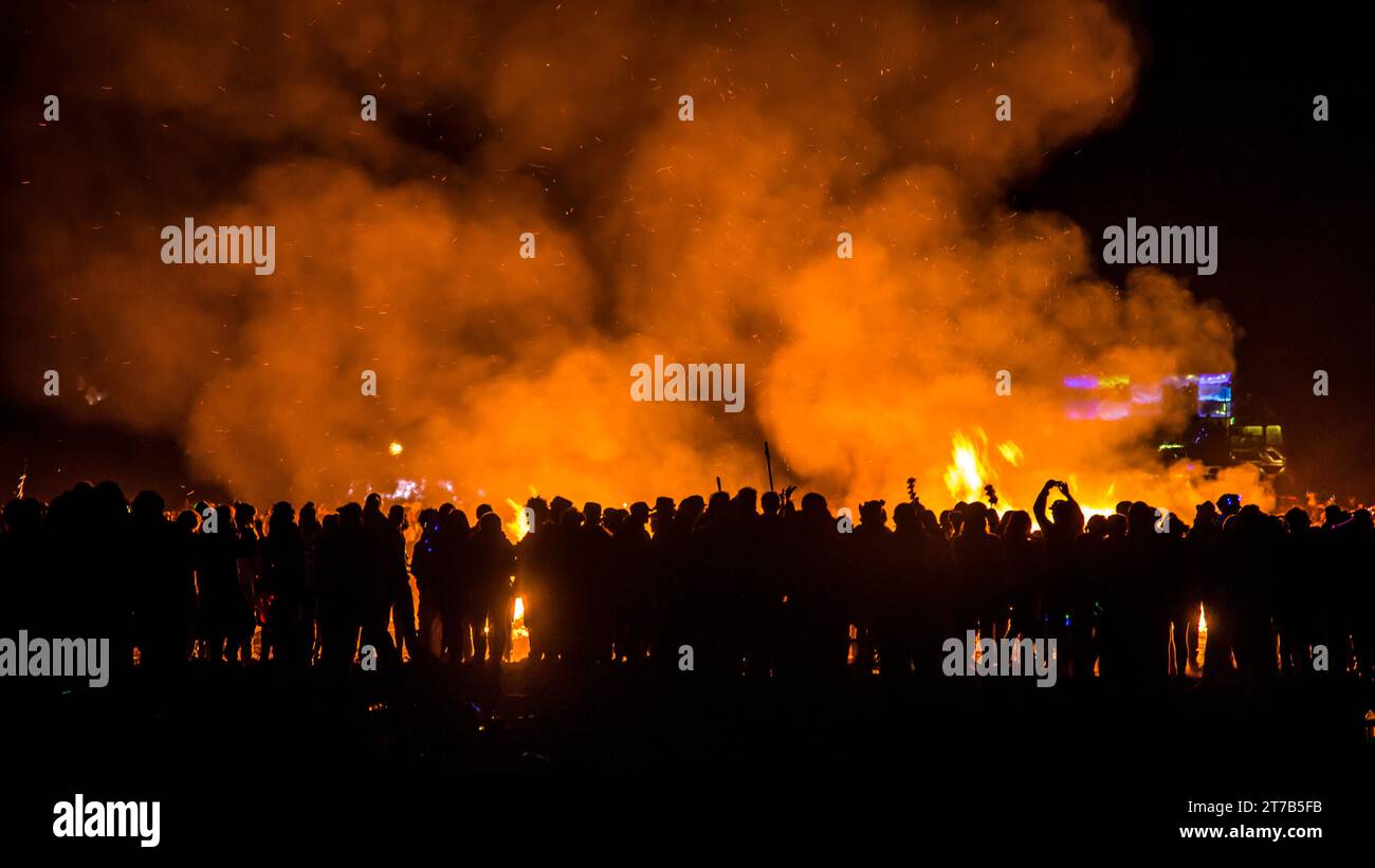 A large group of people gathered together around a bonfire on a stage ...