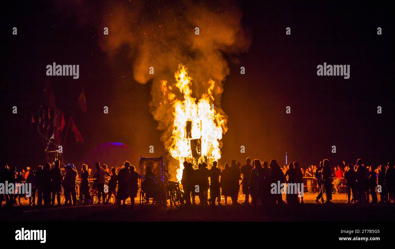 A group of people gather around a warm, blazing bonfire in the evening ...