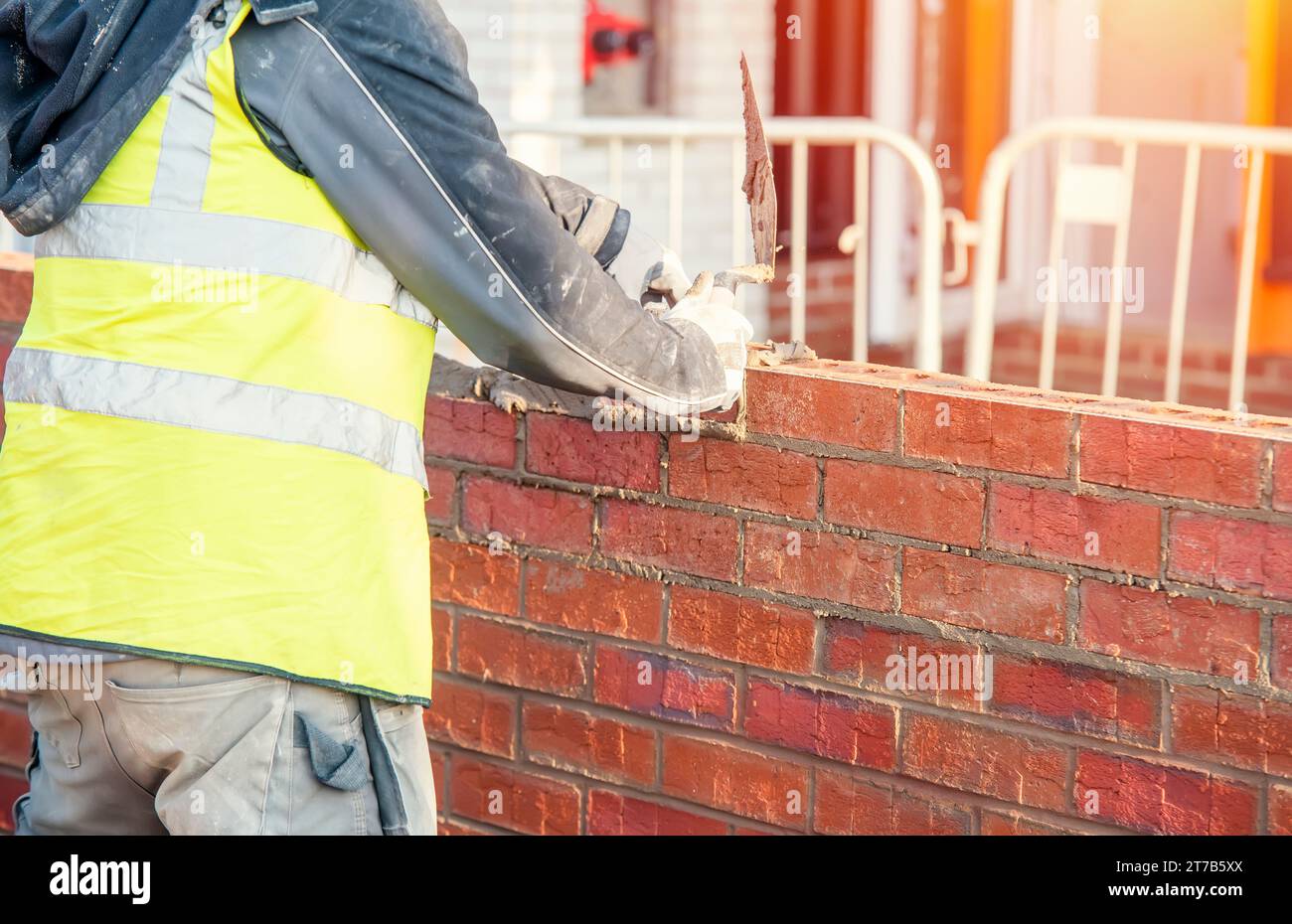 Hard working bricklayer lays bricks on cement mix on construction site ...