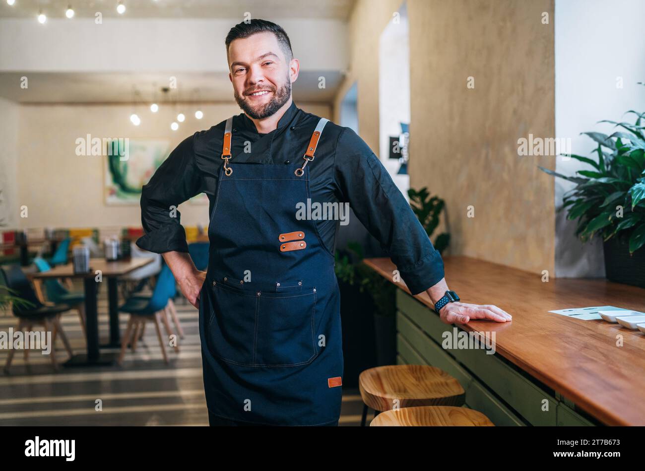 Portrait of happy smiling small business owner dressed in a black chef ...