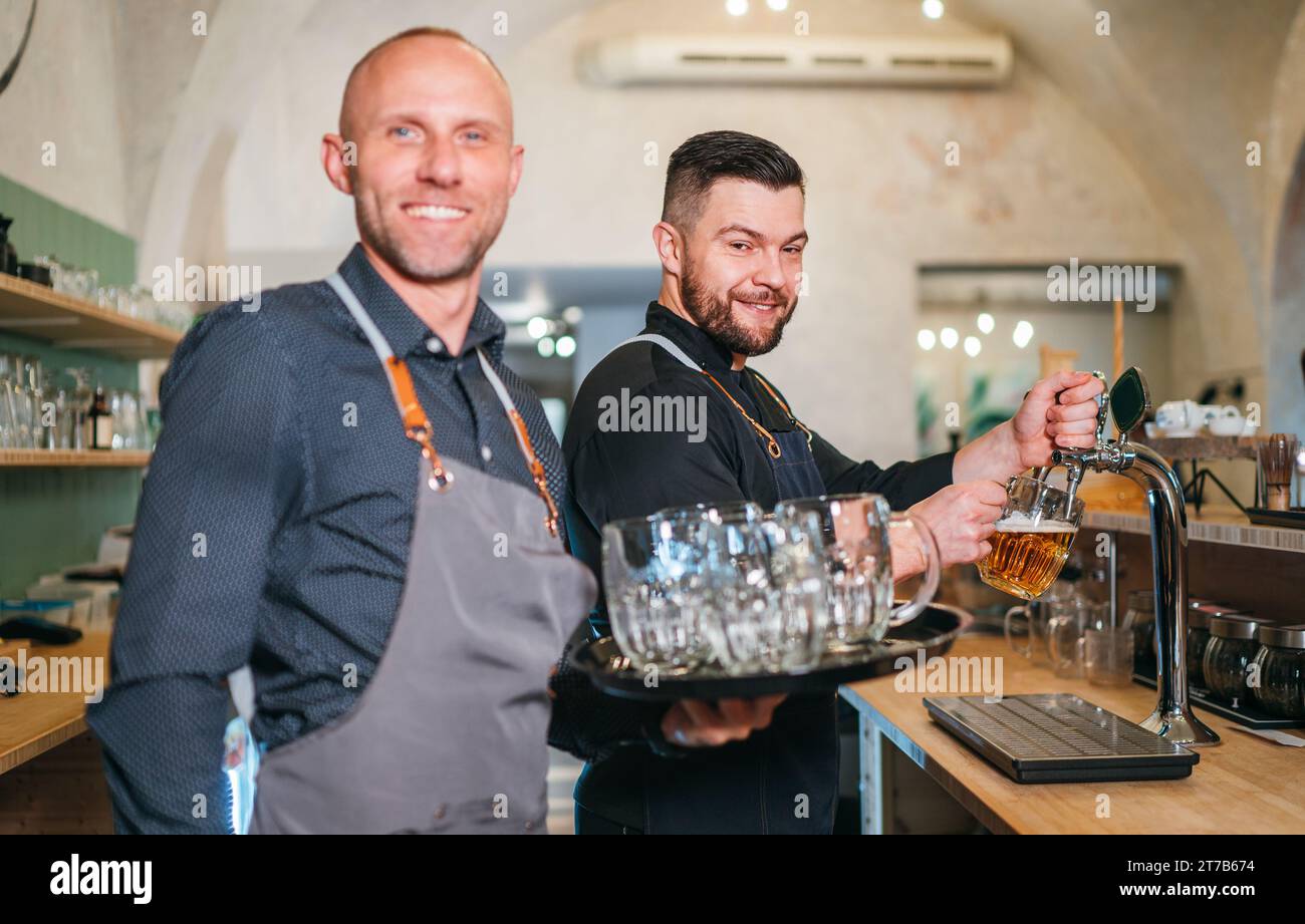 Stylish bearded barman dressed black uniform beer tapping at bar ...