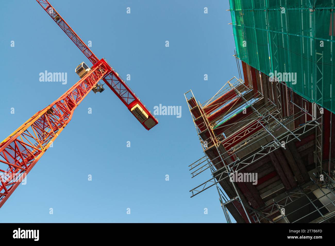 Bottom view of a tower crane and a house under construction surrounded ...