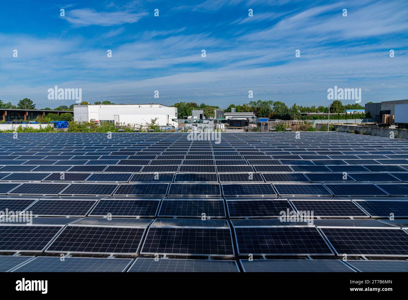 View of multiple solar panels in an industrial area. Blue sky with ...
