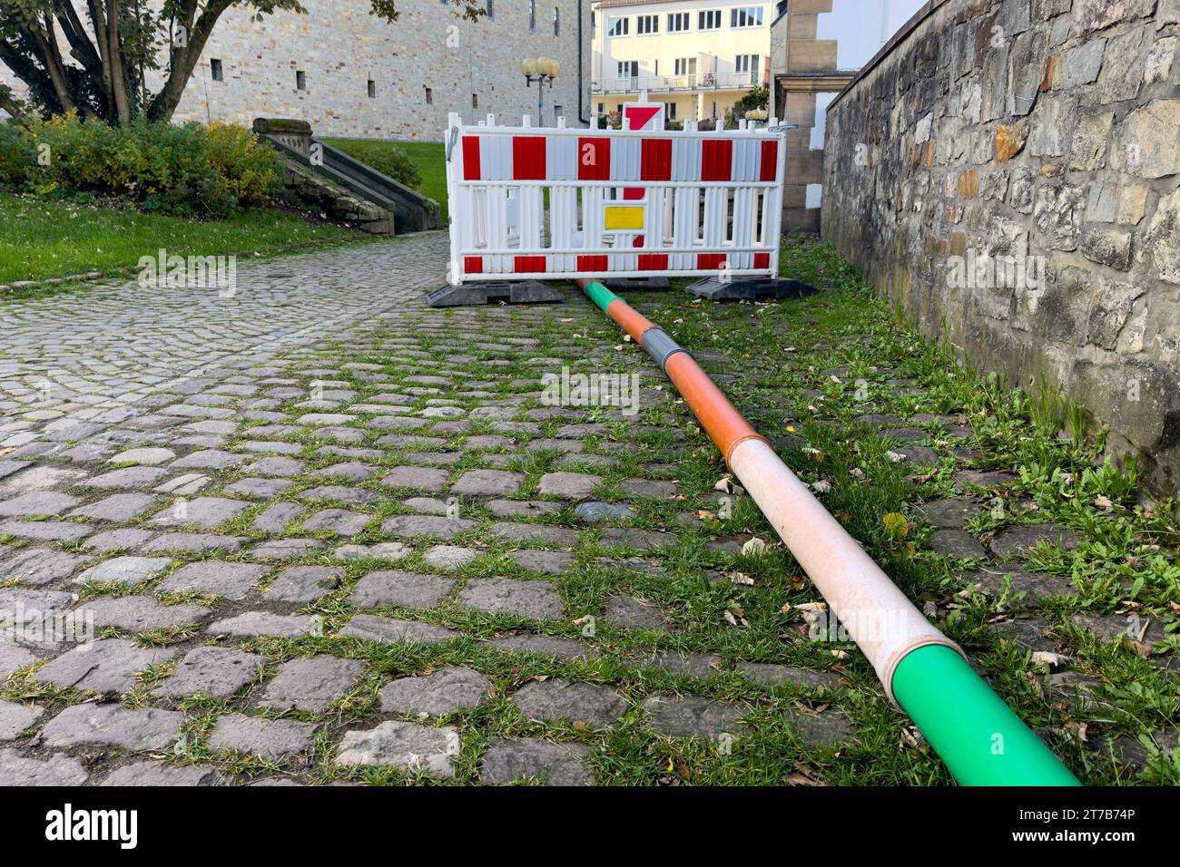 A multi-colored plastic pipe lying on a pedestrian path leading to a ...