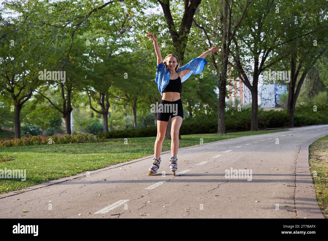Roller skating girl in park skating on inline skates raising arms Stock ...