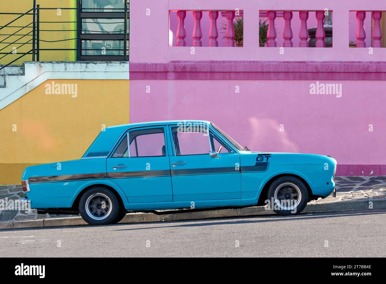 Colorful image of a light-blue vintage Opel GT in front of a yellow and ...