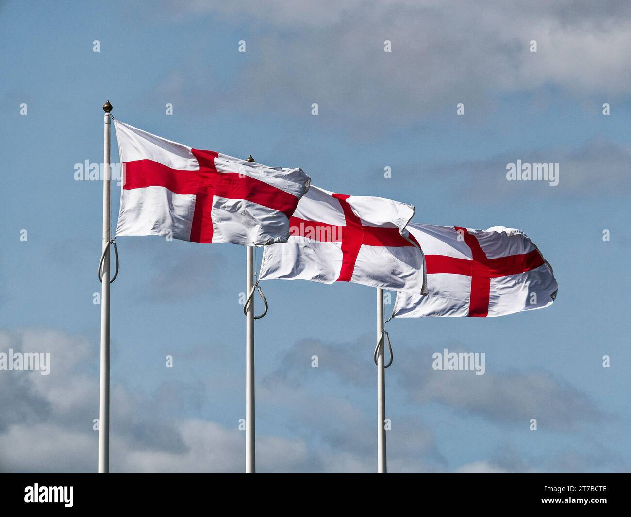 Three flags bearing the cross of Saint George flutter against a blue ...