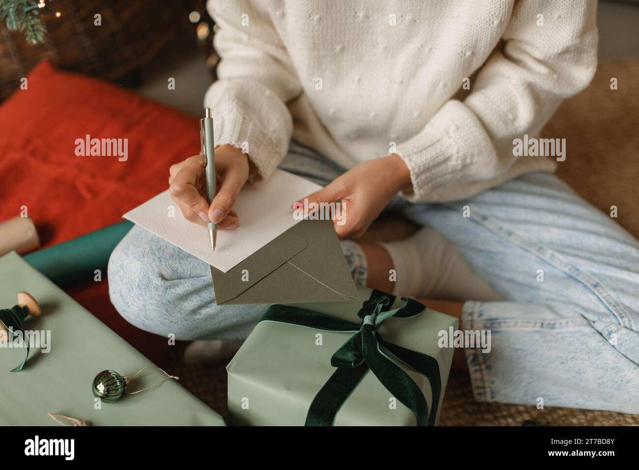 Close-up of a woman sitting cross-legged on the floor next to a wrapped ...