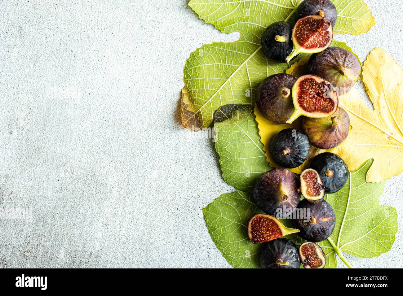 Overhead view of fresh organic figs on an arrangement of fig leaves ...