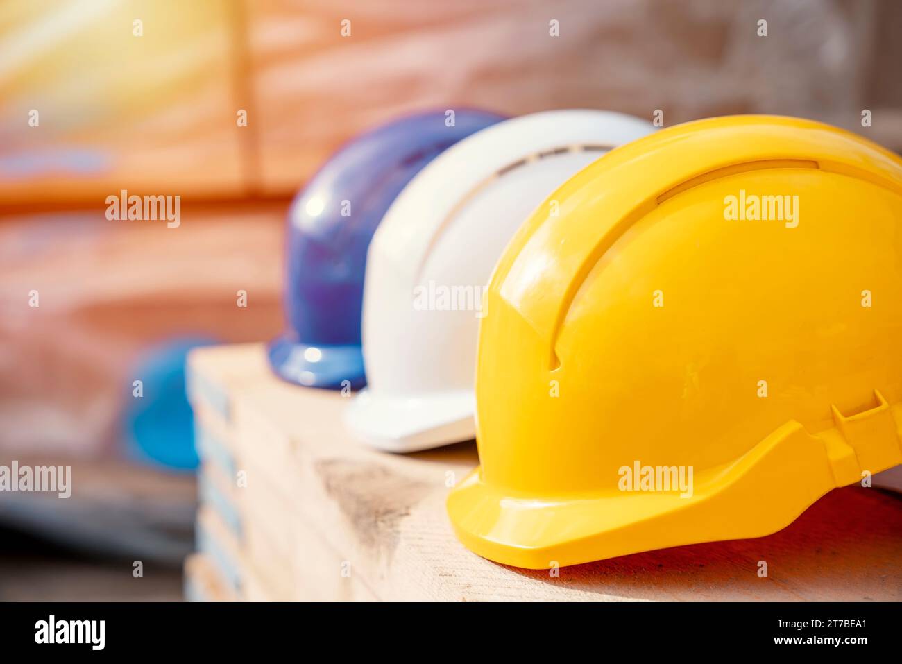 Three helmets of different colors on top of timber board close-up with ...