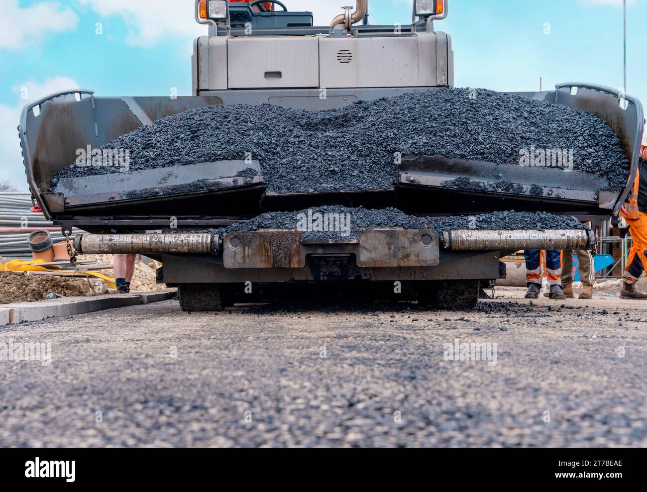 Asphalt paver filled with hot tarmac laying new road surface on new ...