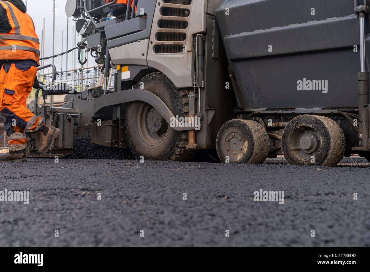 Asphalt paver filled with hot tarmac laying new road surface on new ...