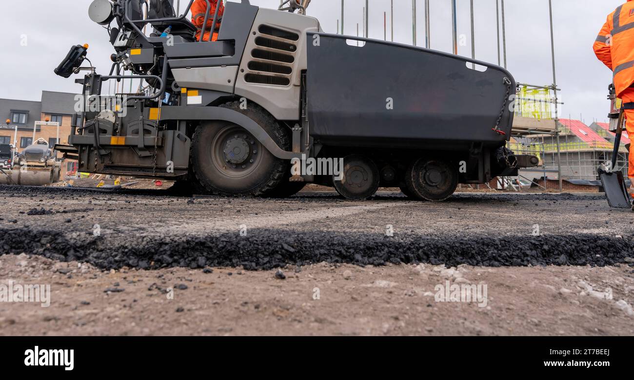 Asphalt paver filled with hot tarmac laying new road surface on new ...