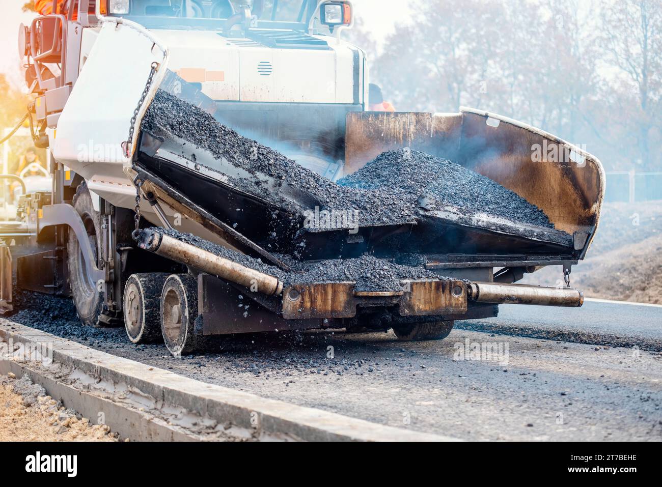 Asphalt paver filled with hot tarmac laying new road surface on new ...